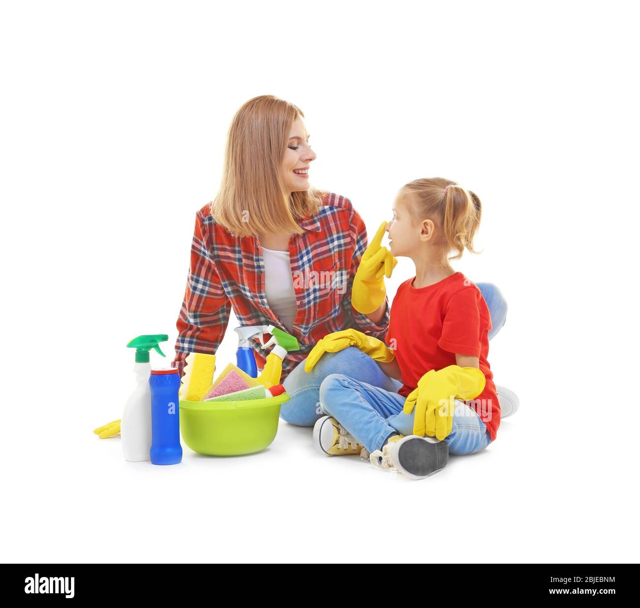 Little girl and her mother with cleaning supplies on white background ...