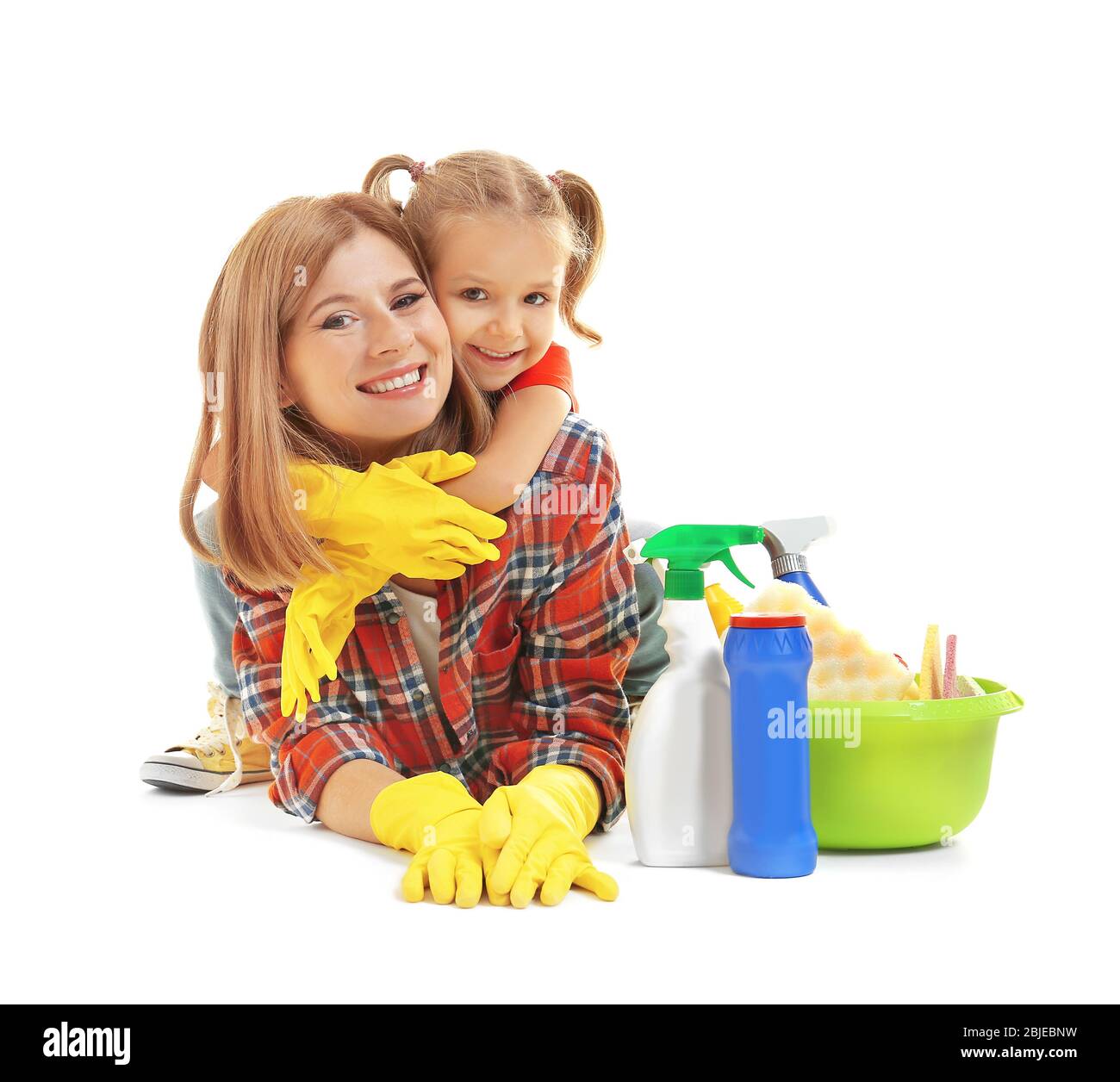 Little girl and her mother with cleaning supplies on white background ...