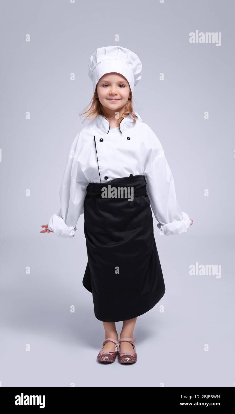 Cute girl in chef uniform on light background Stock Photo - Alamy