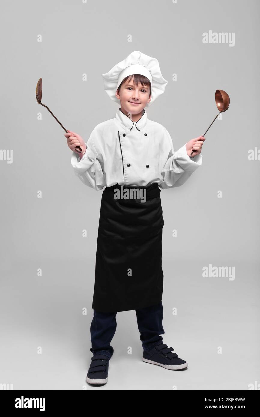 Cute boy in chef uniform on light background Stock Photo - Alamy