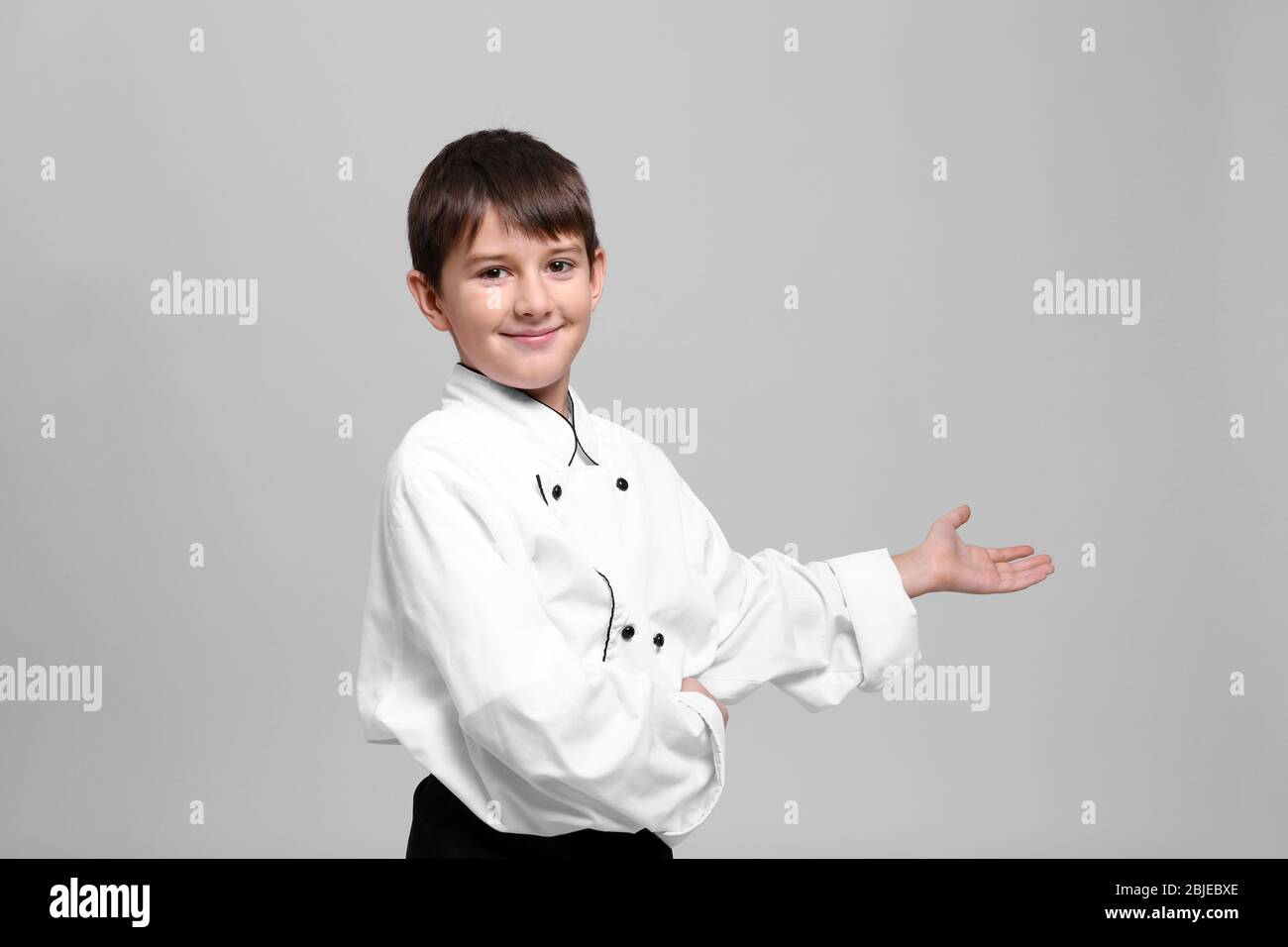 Cute boy in chef uniform on light background Stock Photo - Alamy