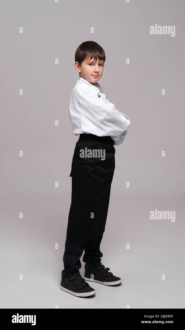 Cute boy in chef uniform on light background Stock Photo - Alamy