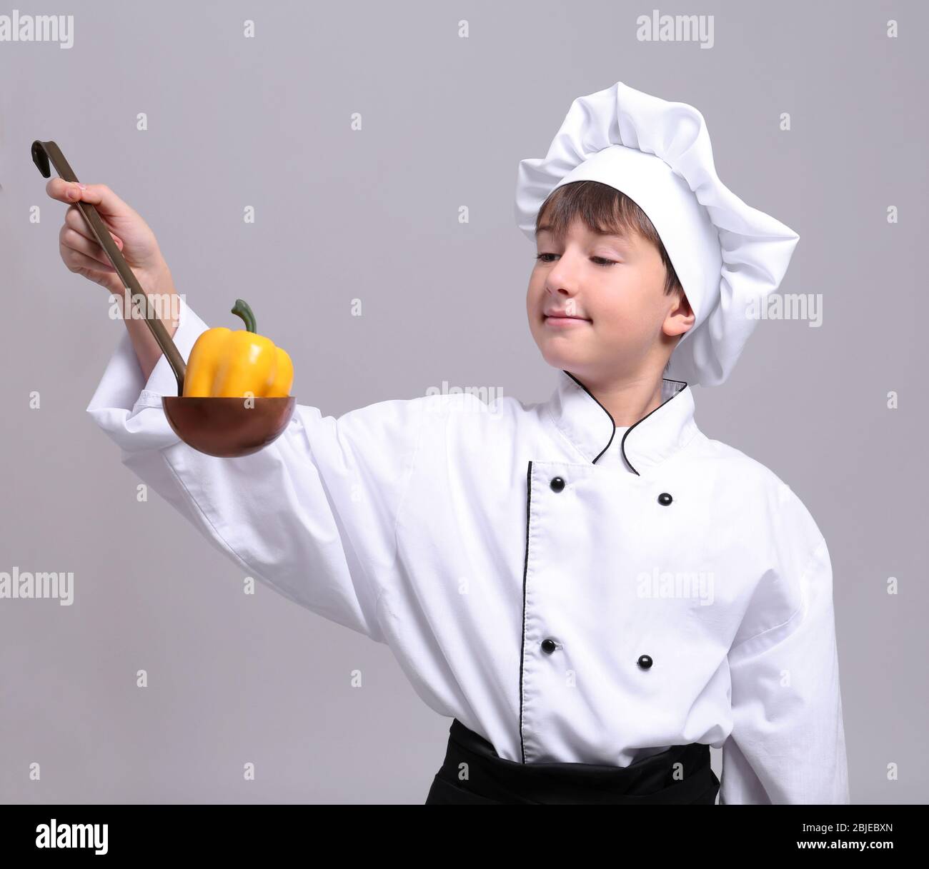 Cute boy in chef uniform on light background Stock Photo - Alamy
