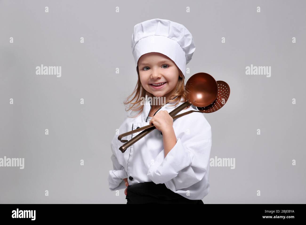 Cute girl in chef uniform on light background Stock Photo - Alamy