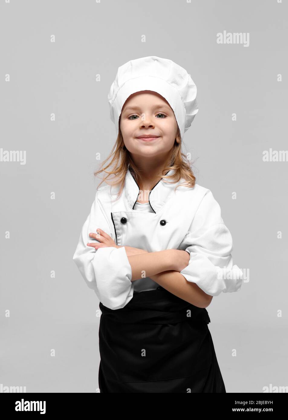 Cute girl in chef uniform on light background Stock Photo - Alamy