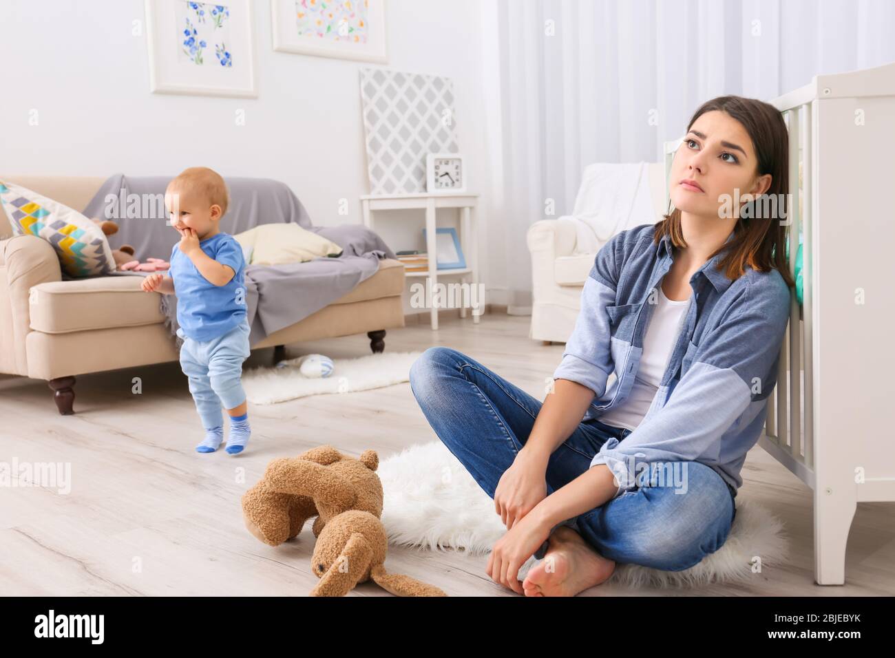 Depressed young woman with cute baby at home Stock Photo - Alamy