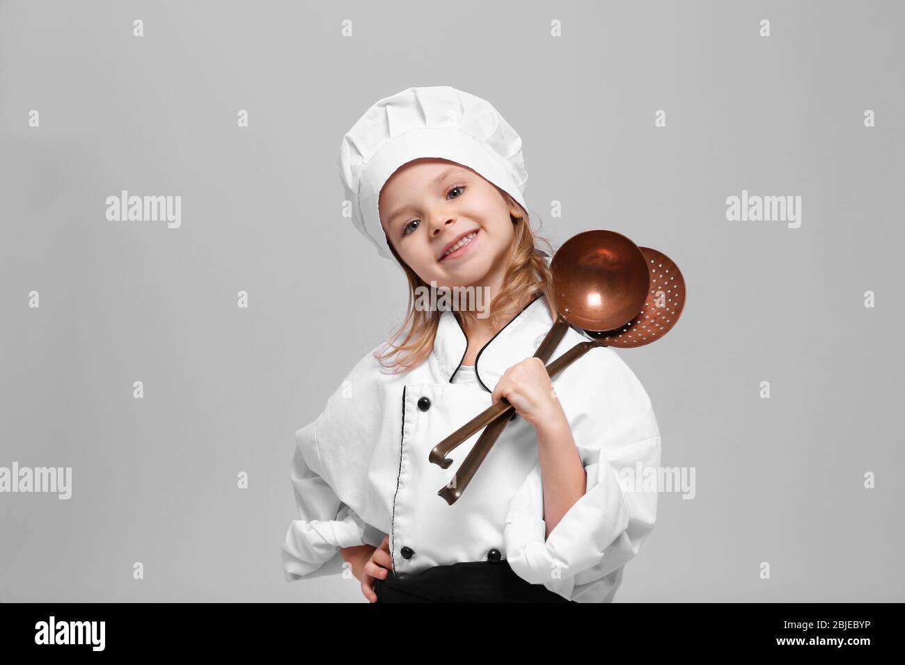 Cute girl in chef uniform on light background Stock Photo - Alamy