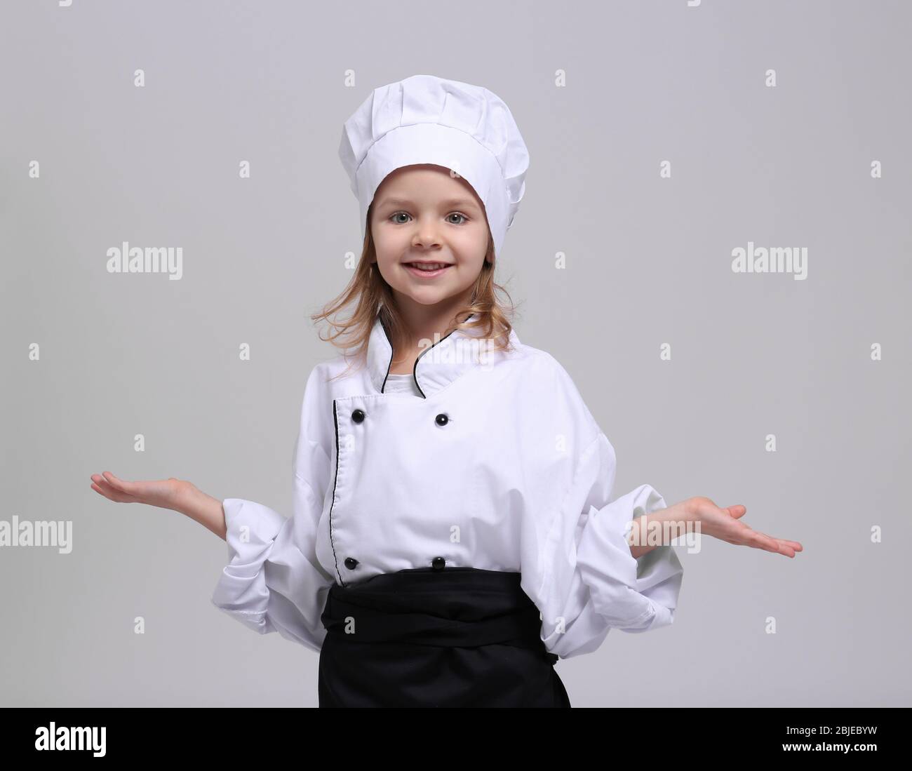 Cute girl in chef uniform on light background Stock Photo - Alamy