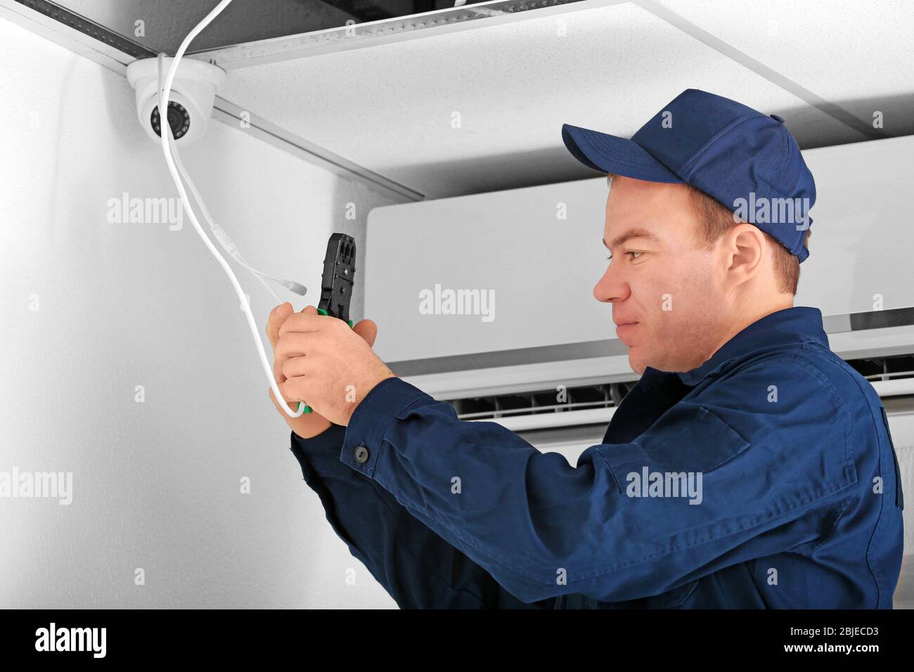 Electrician connecting CCTV camera in office Stock Photo - Alamy
