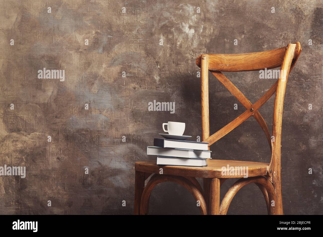 Stack of books on chair against gray wall background Stock Photo - Alamy