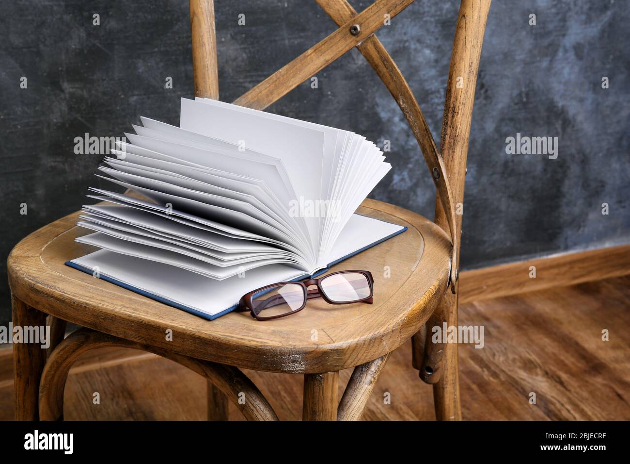 Open book on chair with glasses against gray wall background Stock ...