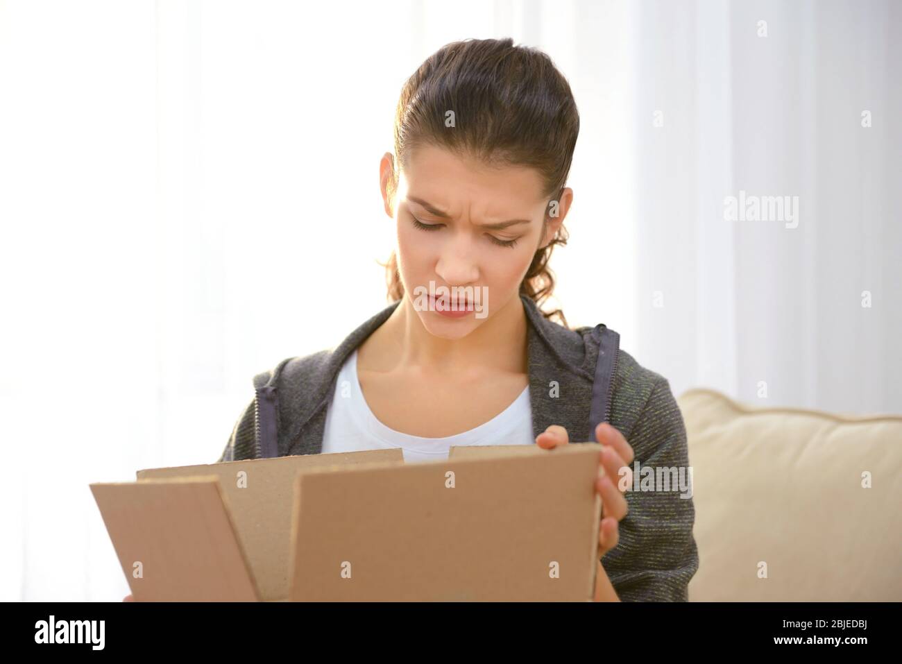 Beautiful young woman opening box with parcel at home Stock Photo - Alamy