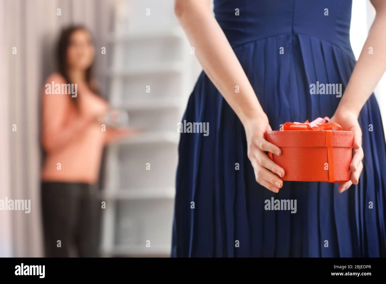 Woman hiding present behind back hi-res stock photography and images ...