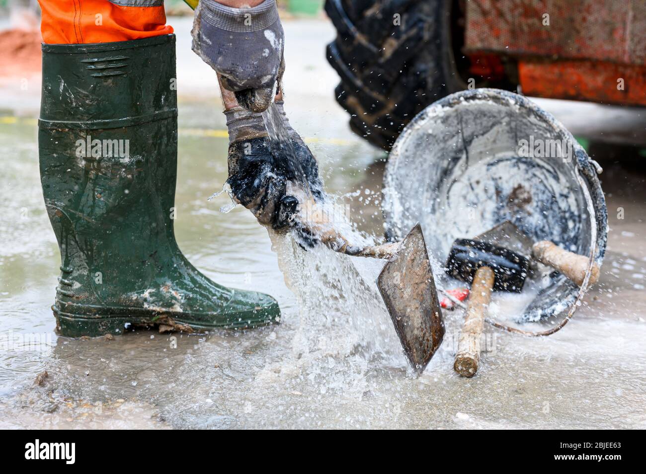 Construction worker washing tools at construction site road street ...
