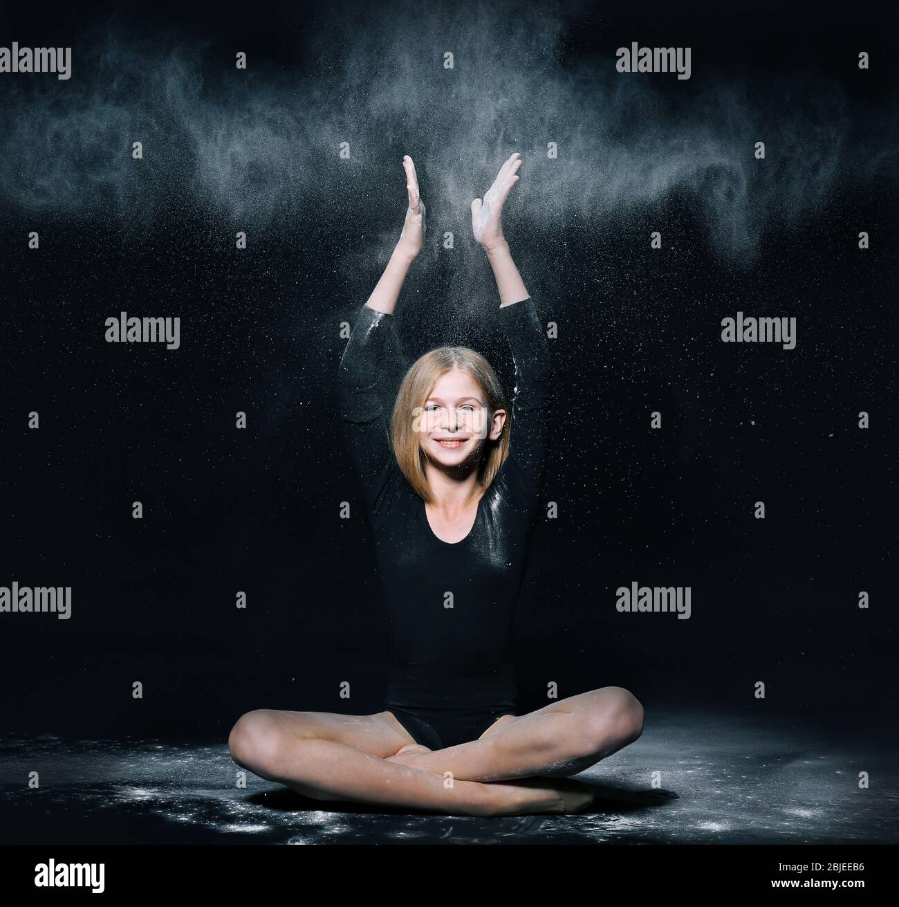 Little cute girl with white powder exploding around her on black ...