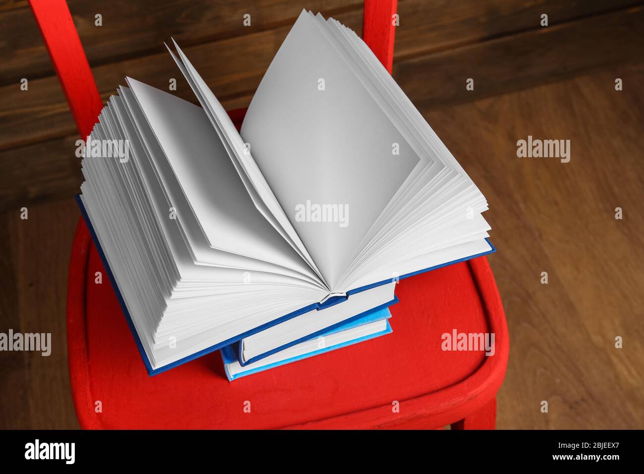 Chair with new books on wooden background Stock Photo - Alamy