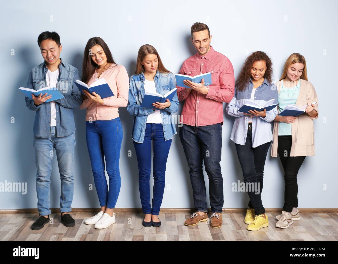Group of people with books standing near light wall Stock Photo - Alamy