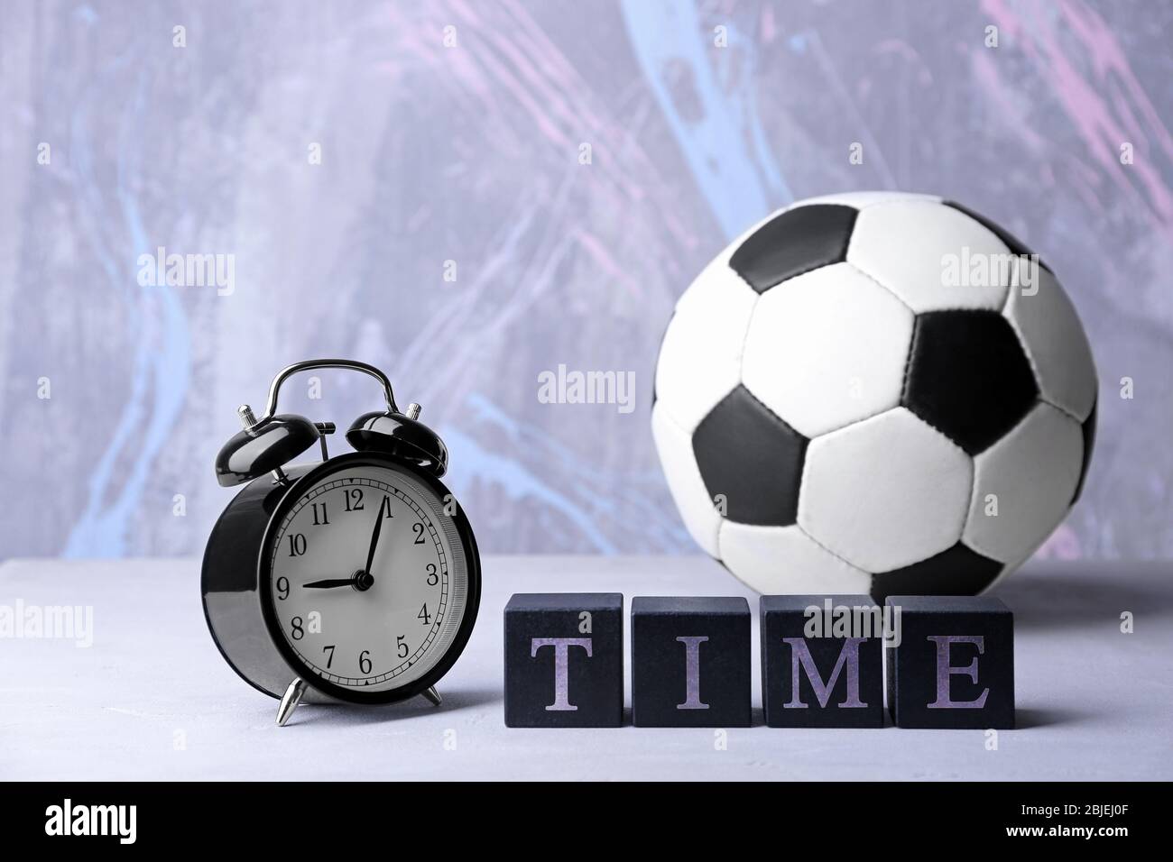Cubes with alarm clock and soccer ball on color background. Time ...