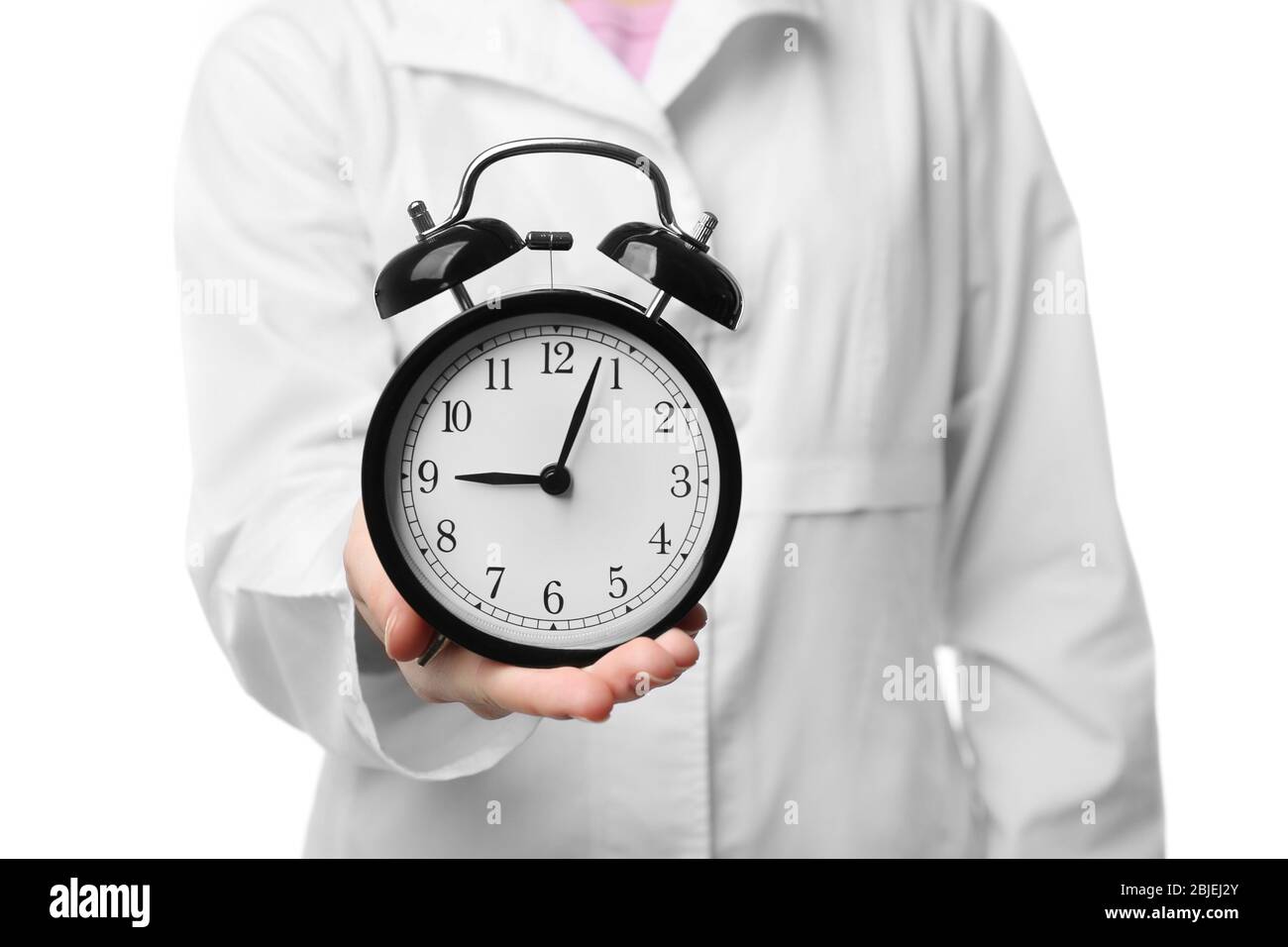Doctor holding alarm clock on white background Stock Photo - Alamy