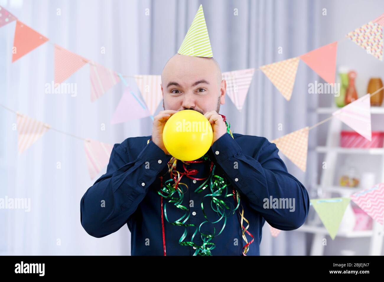 Funny fat man inflating balloon at birthday party Stock Photo - Alamy