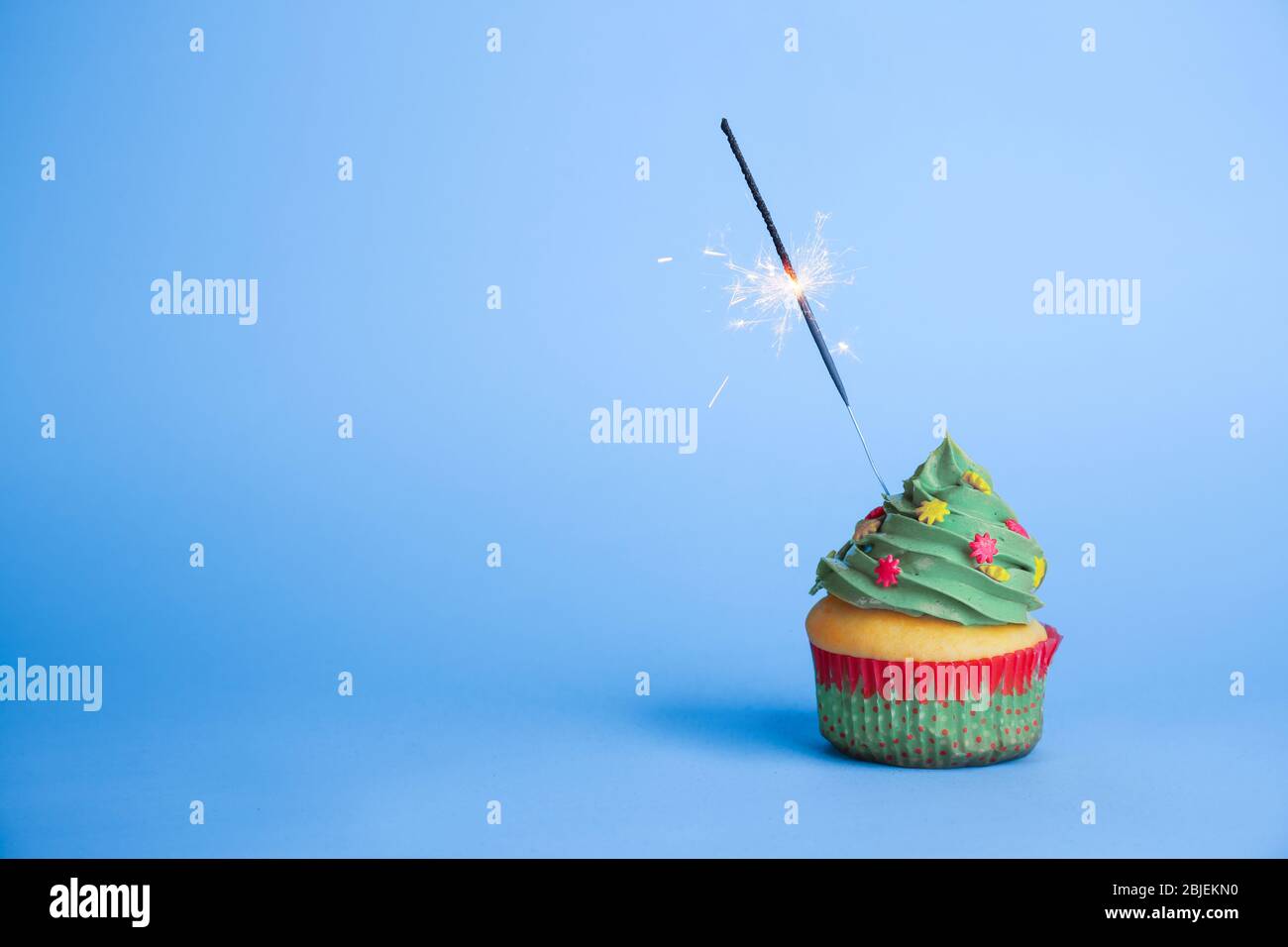 Cupcake with sparkler on color background Stock Photo - Alamy