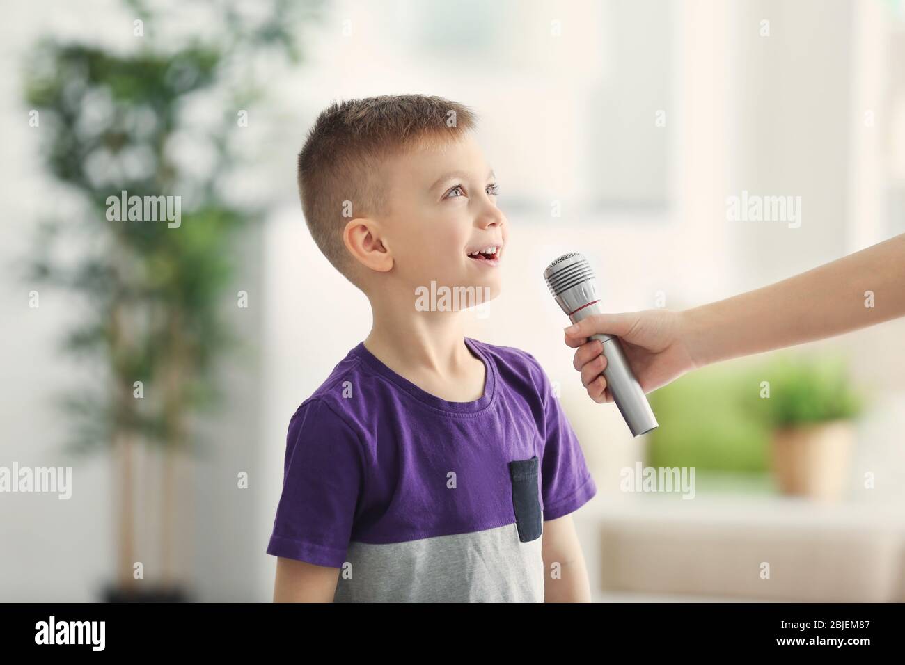 Female hand giving microphone to cute little boy at home Stock Photo ...