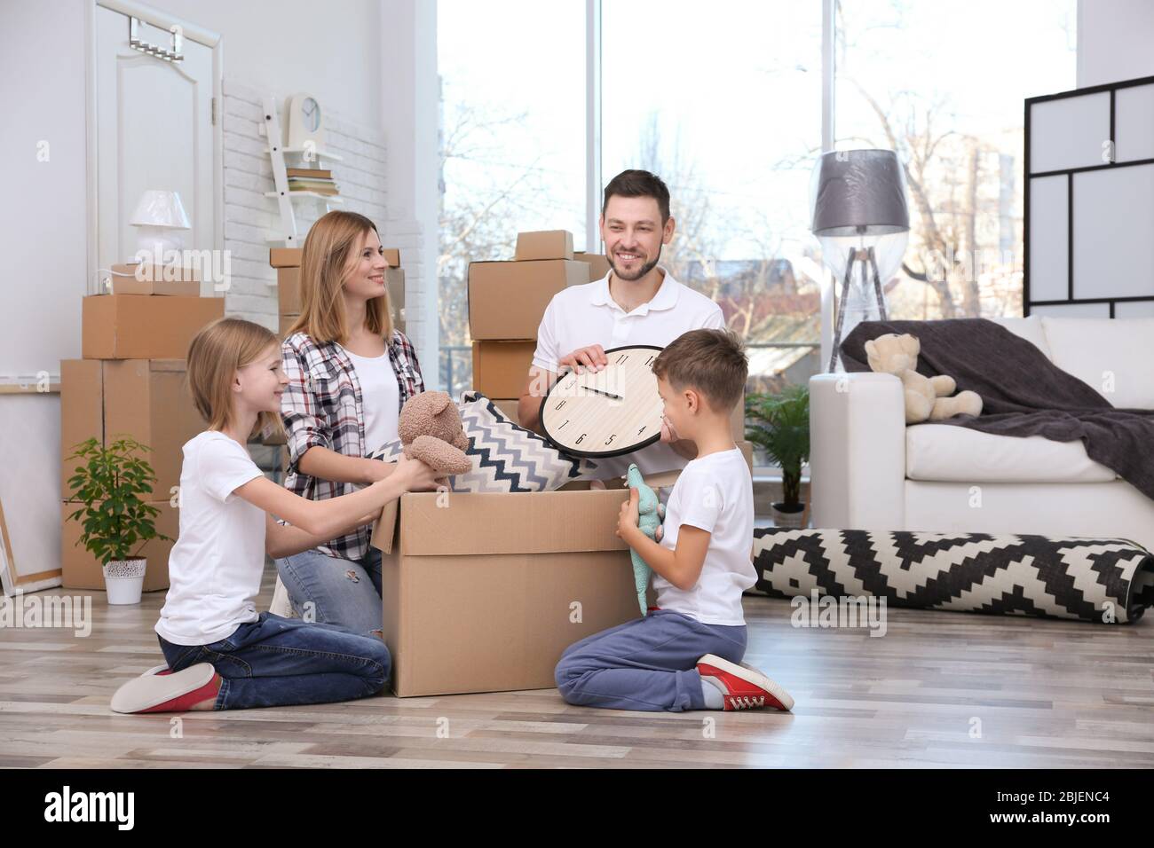 Happy family unpacking cardboard box on floor in new house Stock Photo ...