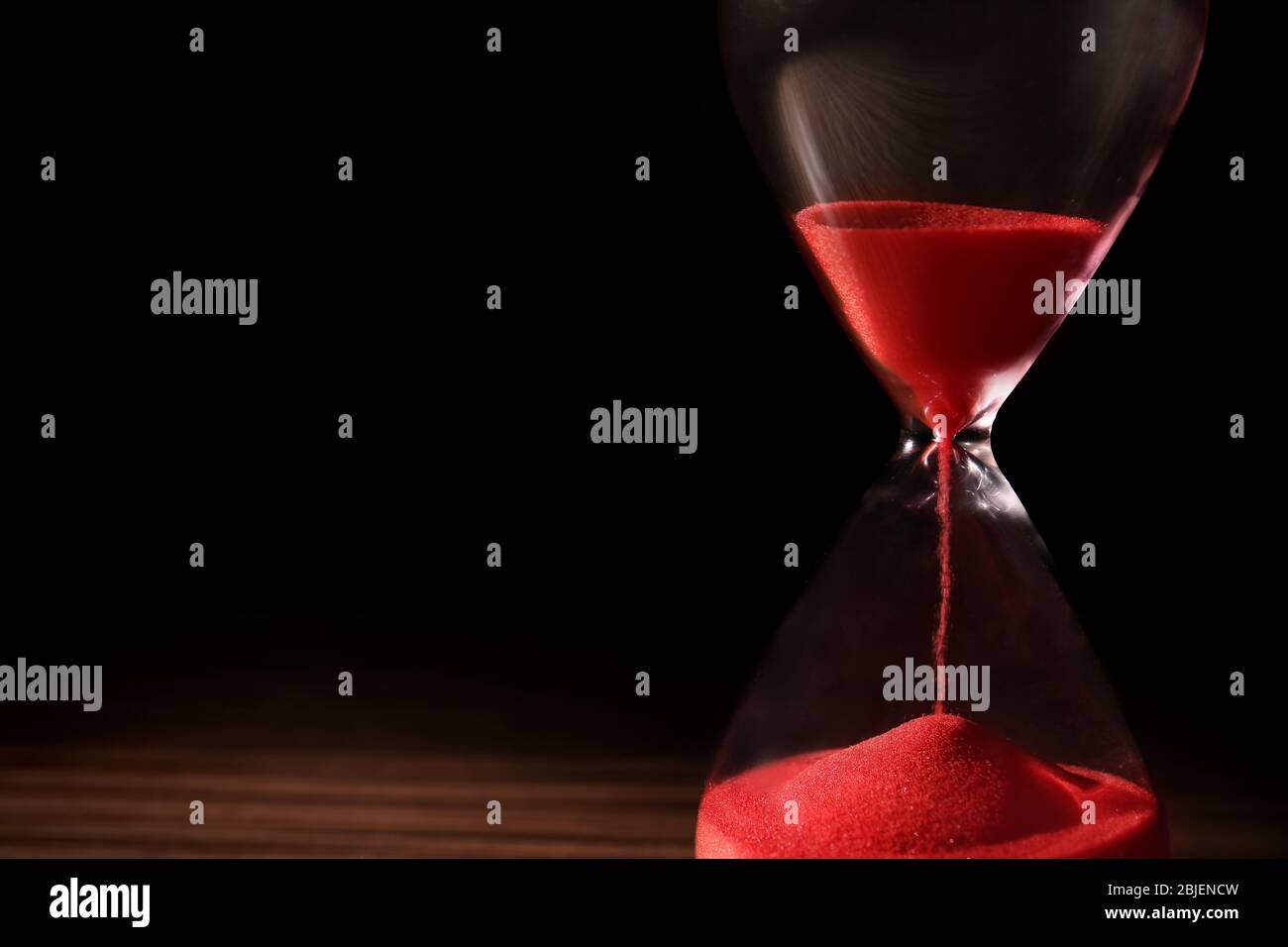 Crystal hourglass with red sand on dark background Stock Photo - Alamy