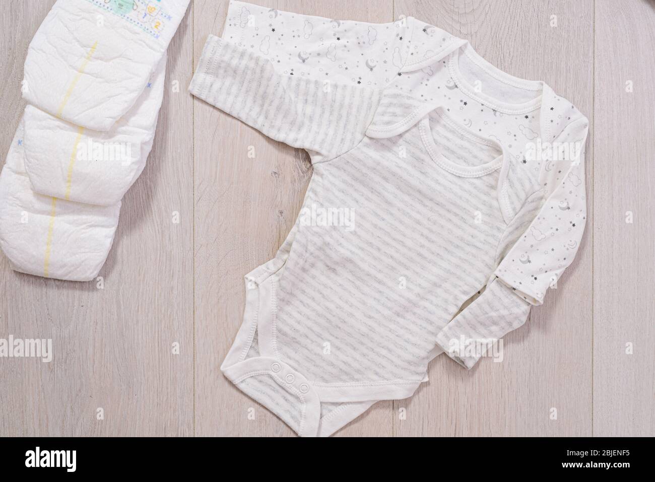 white baby clothes and diapers on wooden background. newborn Stock ...