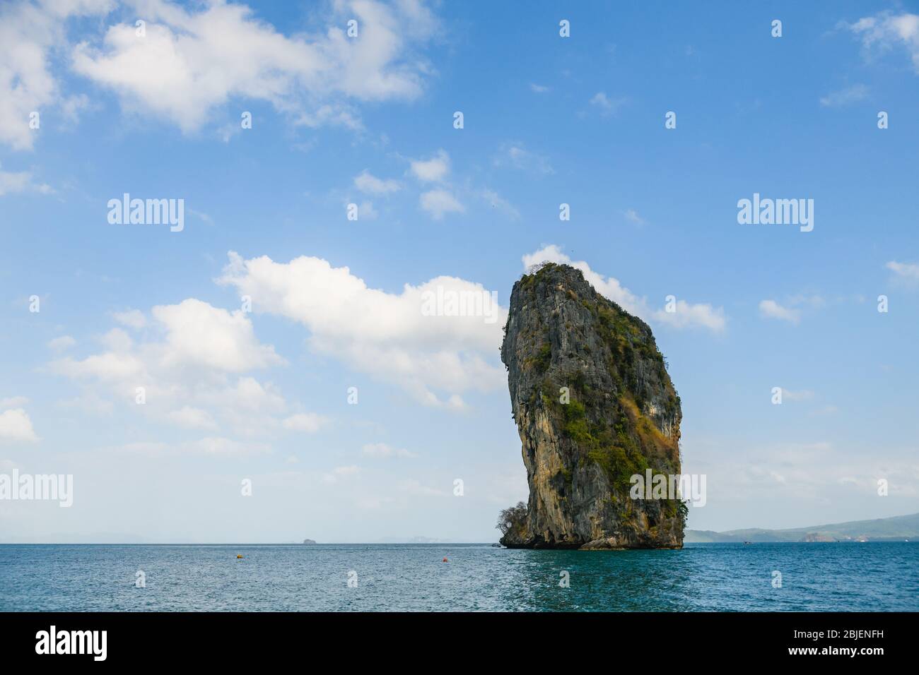 One big long stone rock in middle of sea at horizon with blue sky ...