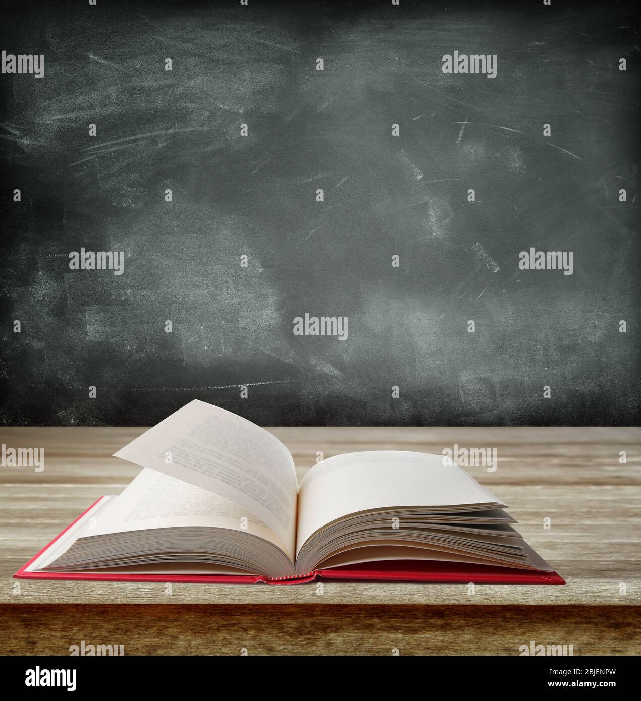 Open book on table in front of blackboard Stock Photo - Alamy