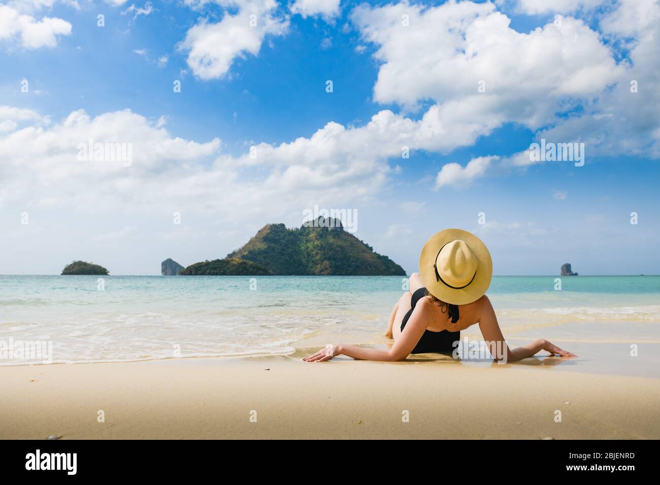 Mysterious female tourist in sun hat and black swimsuit enjoy ...