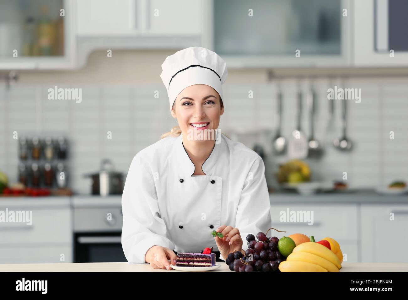 Female chef decorating cake in kitchen Stock Photo - Alamy