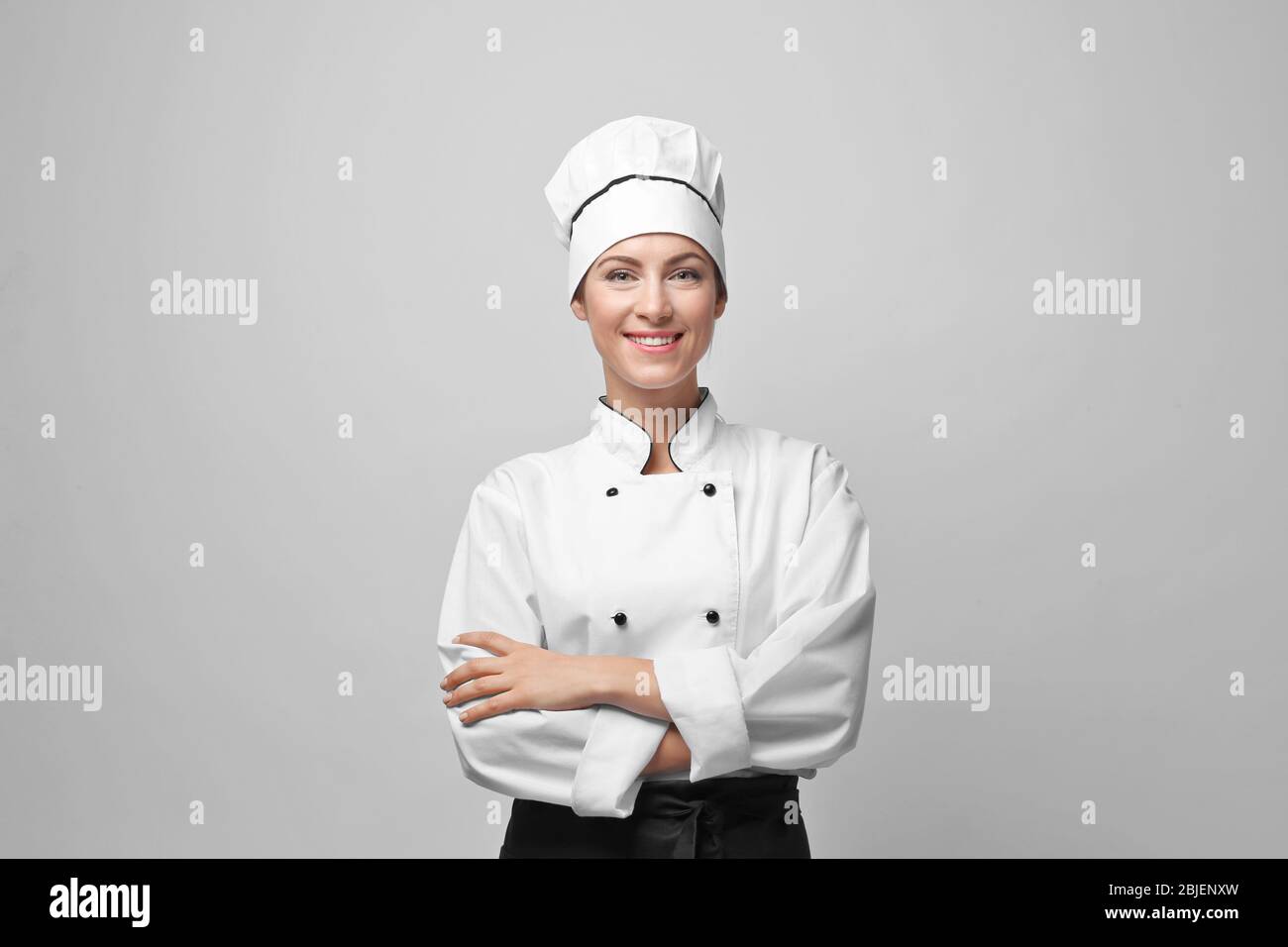 Portrait of female chef on light grey background Stock Photo - Alamy