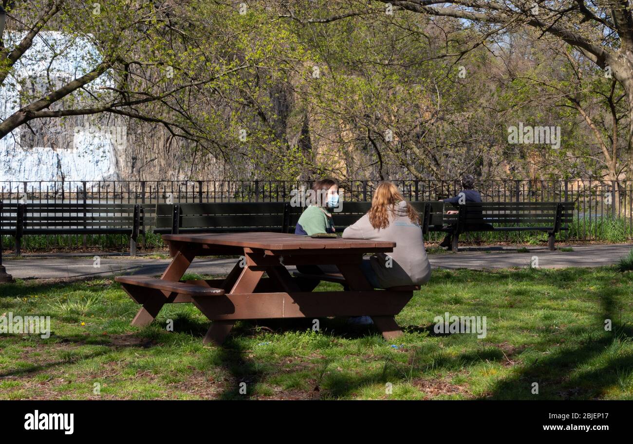 a woman talking to a friend on a picnic table in Inwood Hill Park while ...