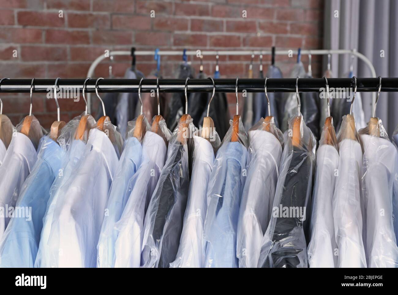 Rack of clean clothes hanging on hangers at dry-cleaning Stock Photo ...