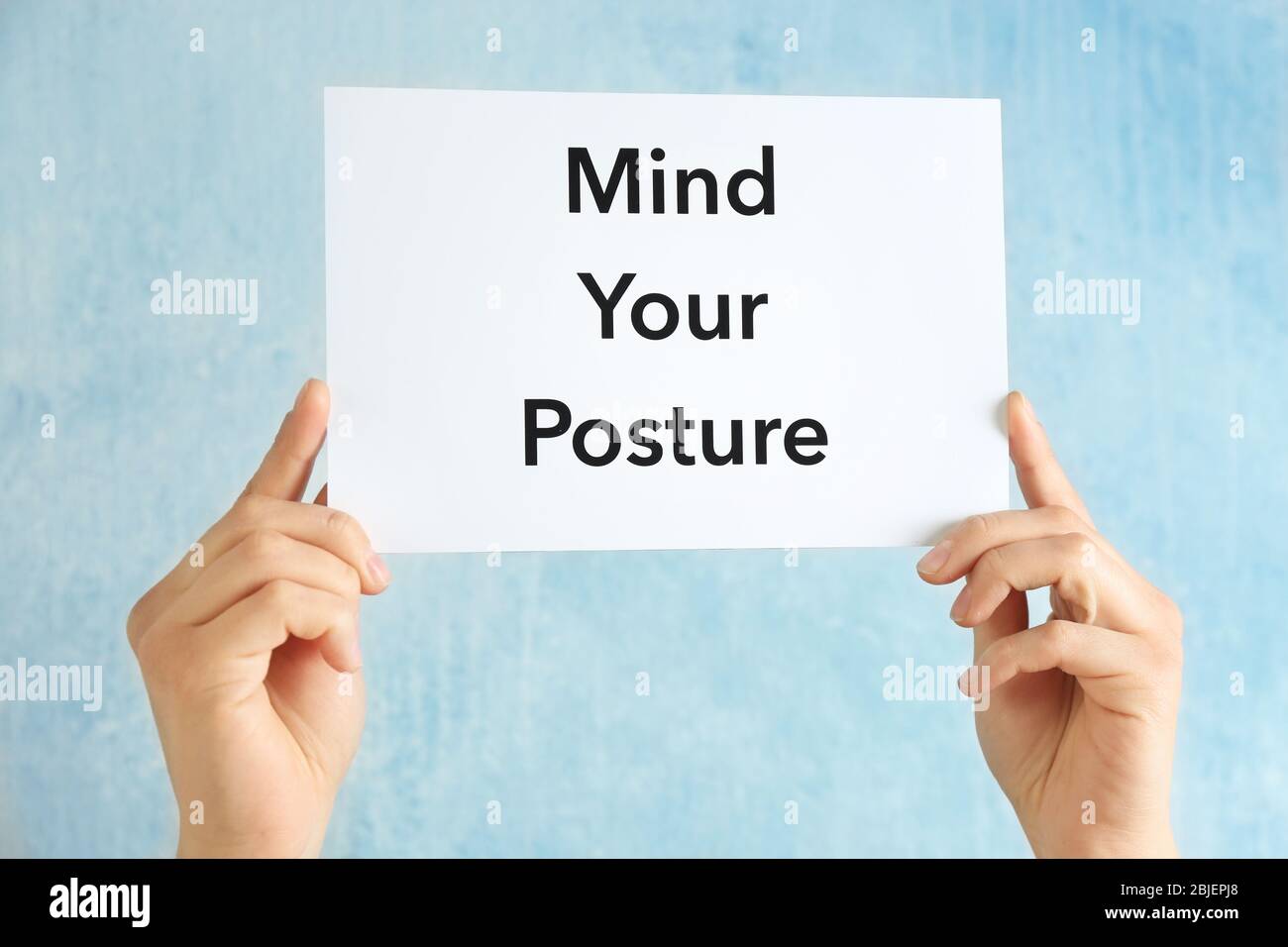 Hands holding paper with phrase MIND YOUR POSTURE on light background ...