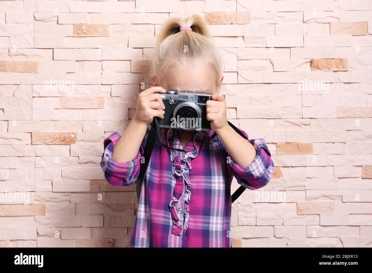 Cute girl with film camera on brick wall background Stock Photo - Alamy