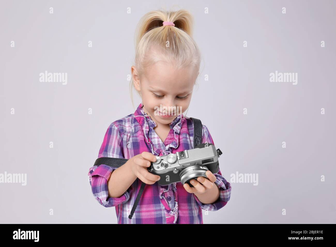 Cute girl with film camera on light background Stock Photo - Alamy