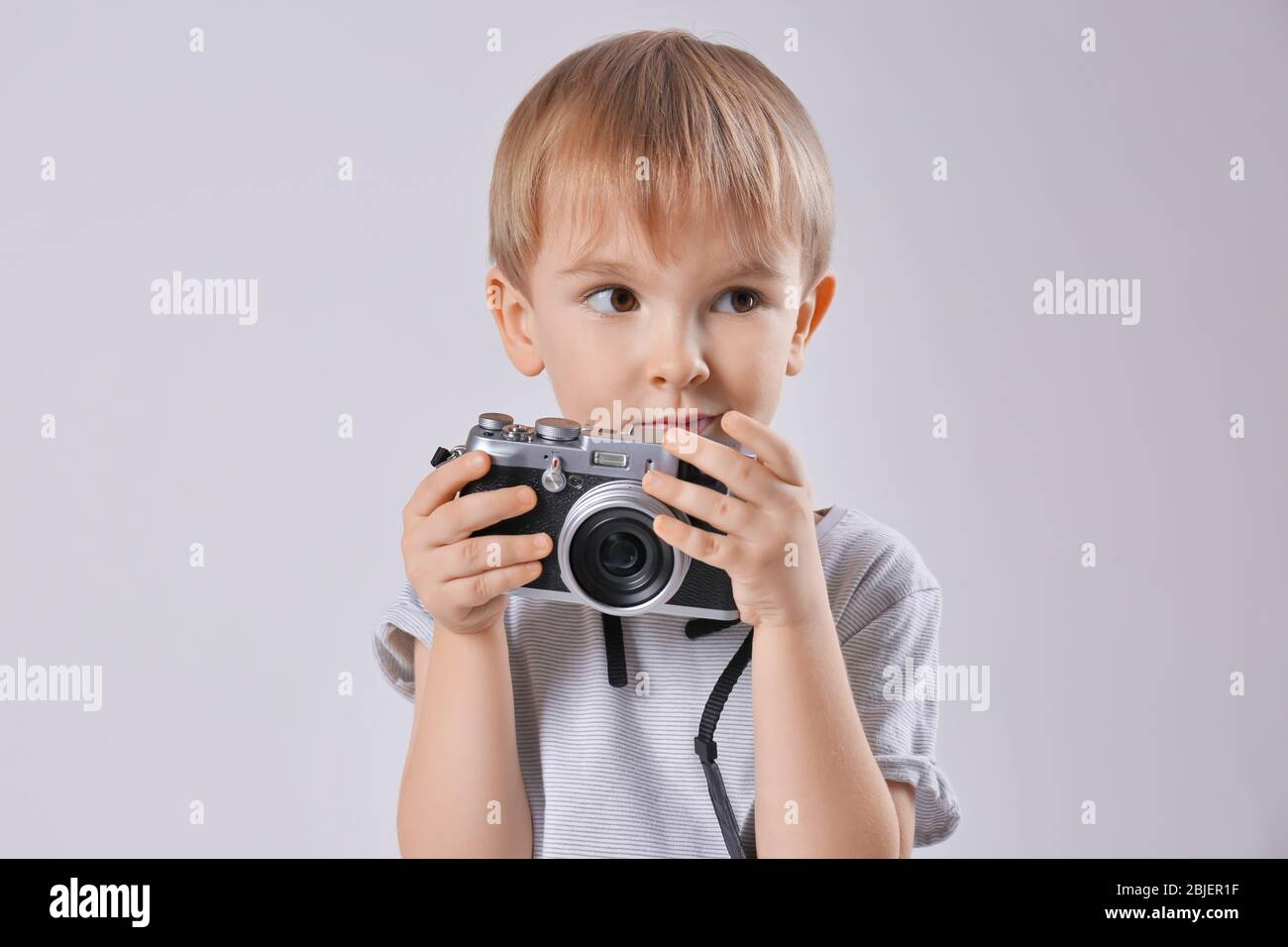 Cute boy with film camera on light background Stock Photo - Alamy