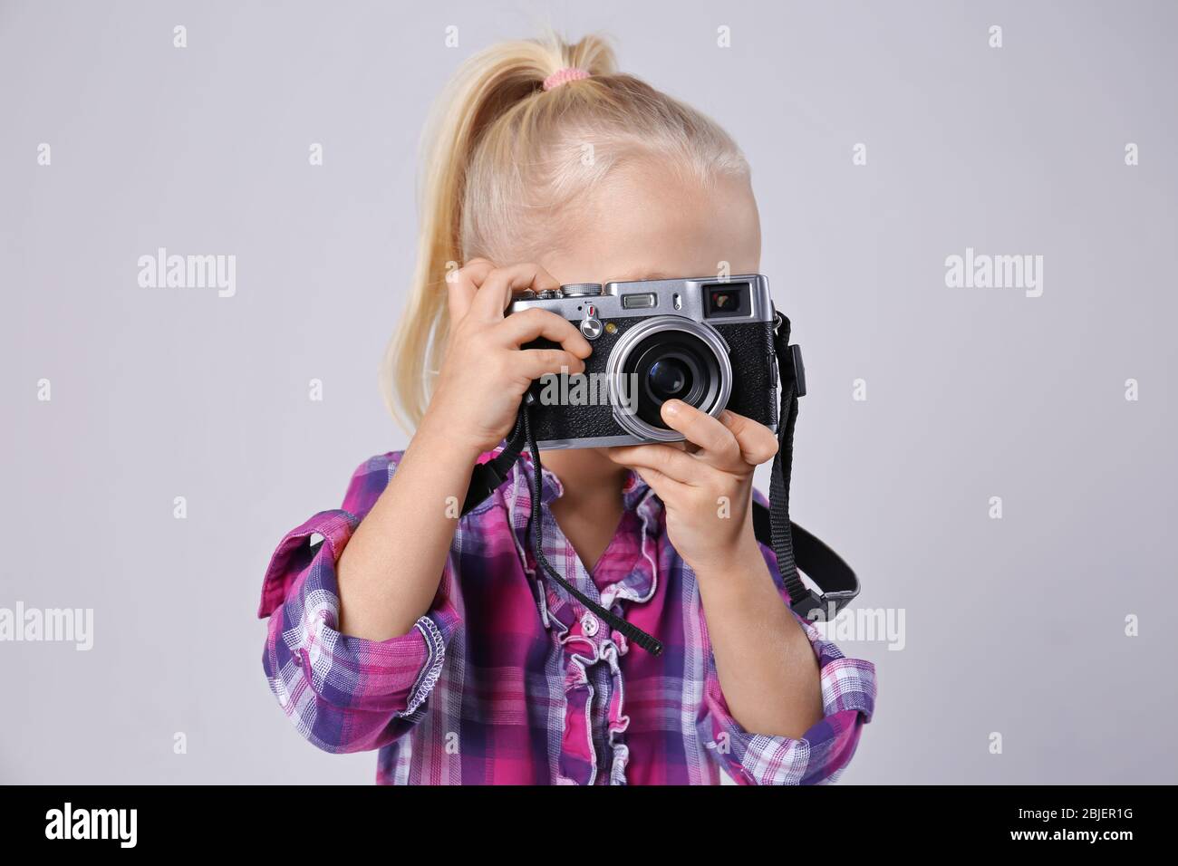 Cute girl with film camera on light background Stock Photo - Alamy