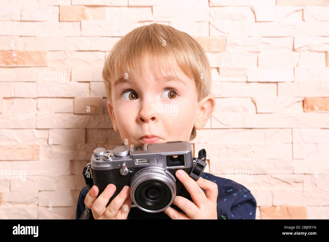 Cute boy with film camera on brick wall background Stock Photo - Alamy