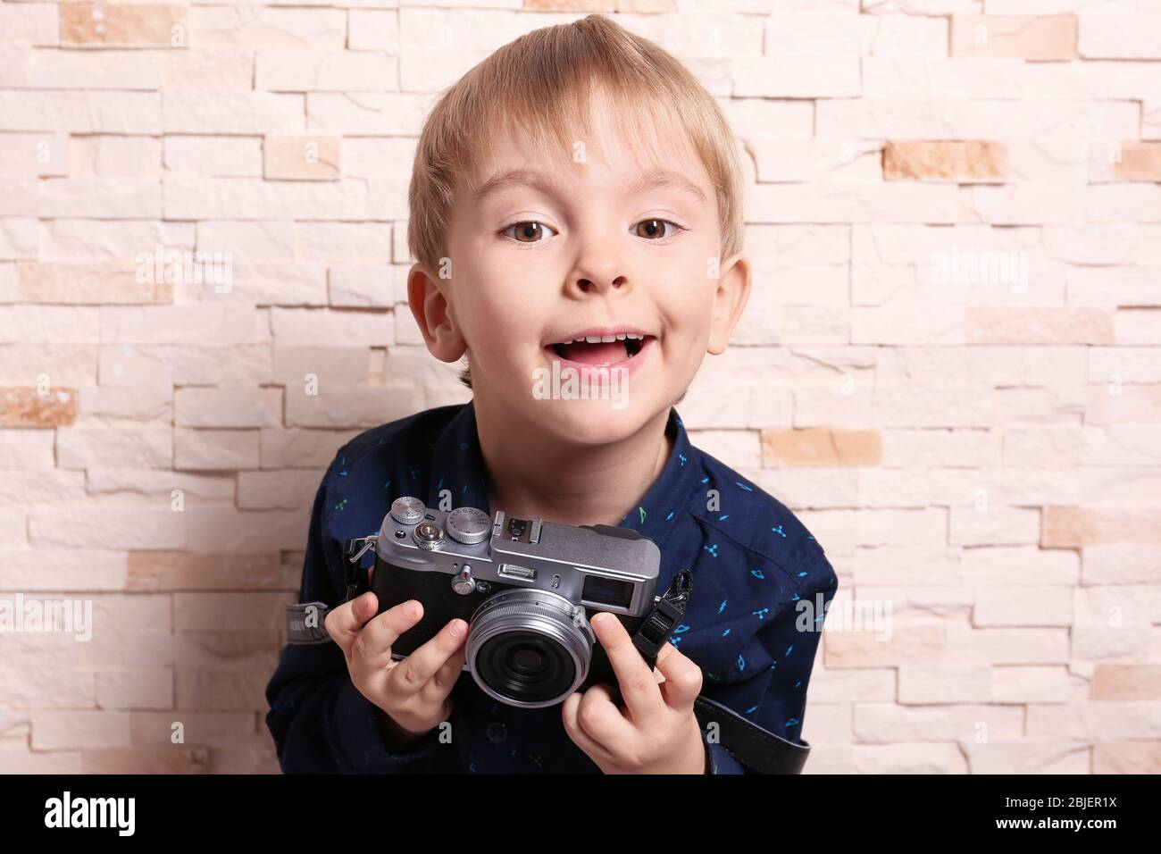 Cute boy with film camera on brick wall background Stock Photo - Alamy