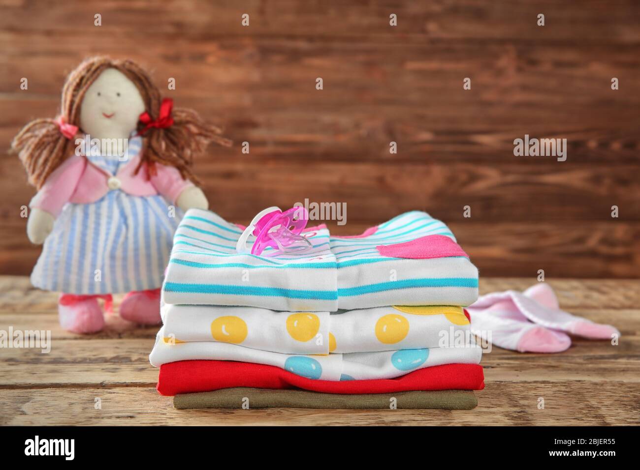 Pile of baby clothes on wooden background Stock Photo - Alamy
