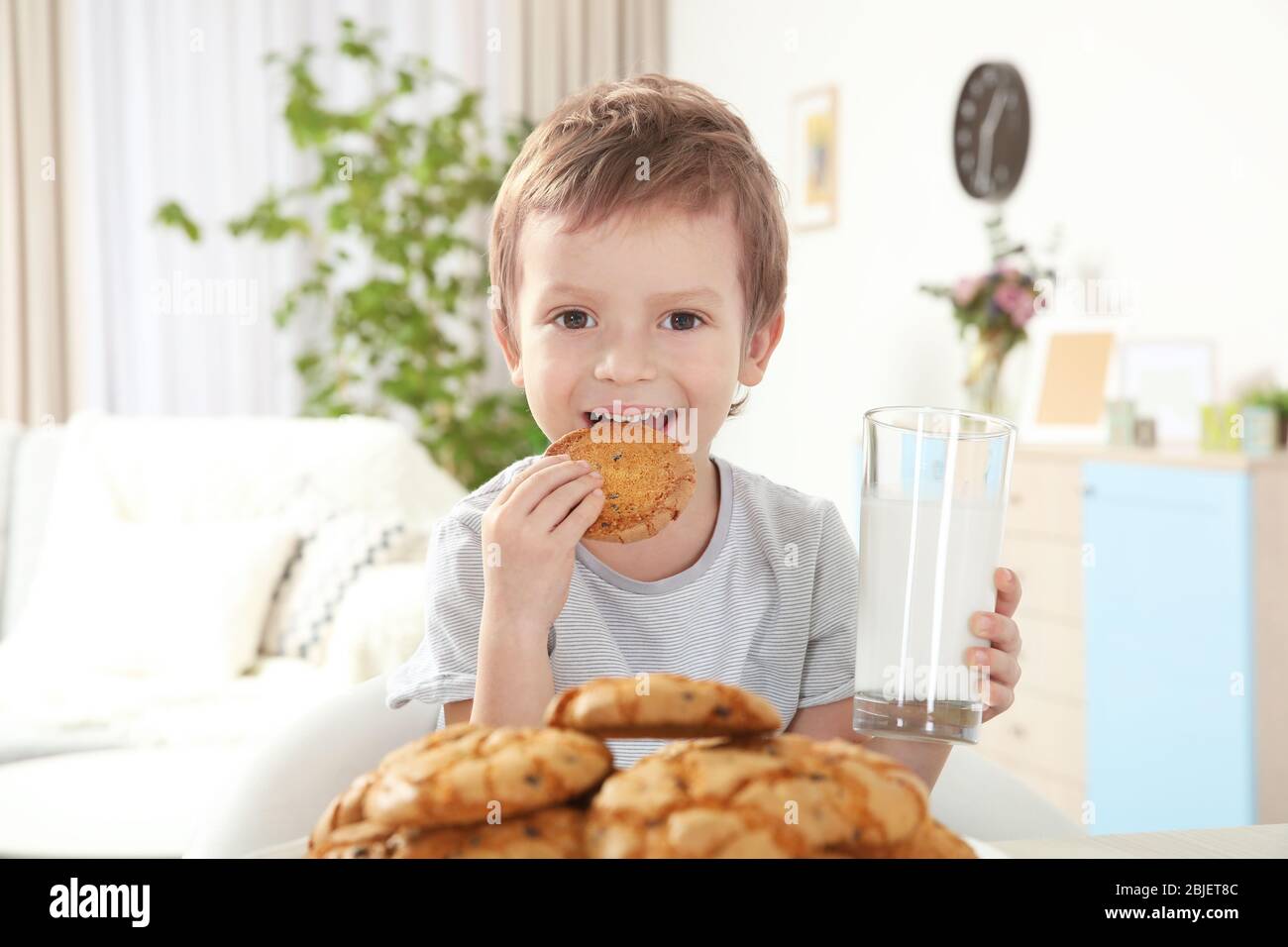 Cute boy eating cookie at home Stock Photo - Alamy