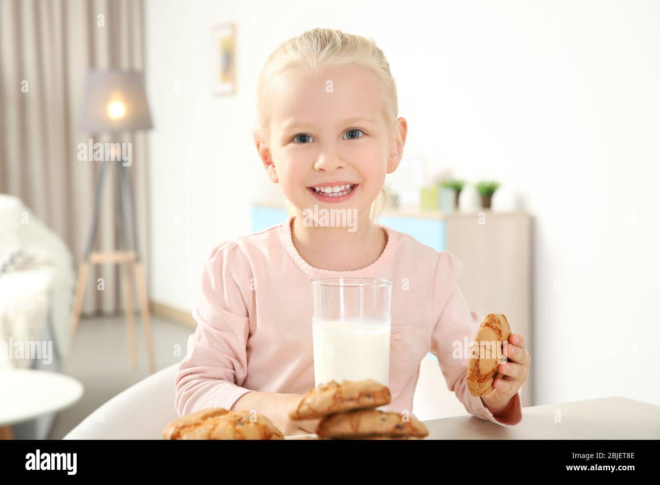 Cute girl eating cookie at home Stock Photo - Alamy