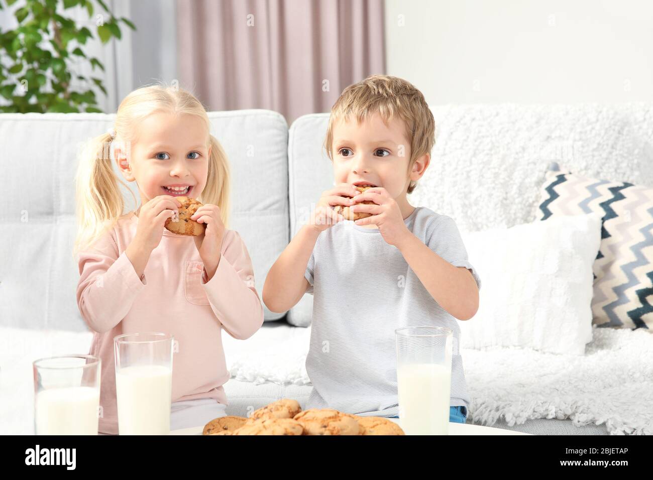 Little kids eating cookies at home Stock Photo - Alamy