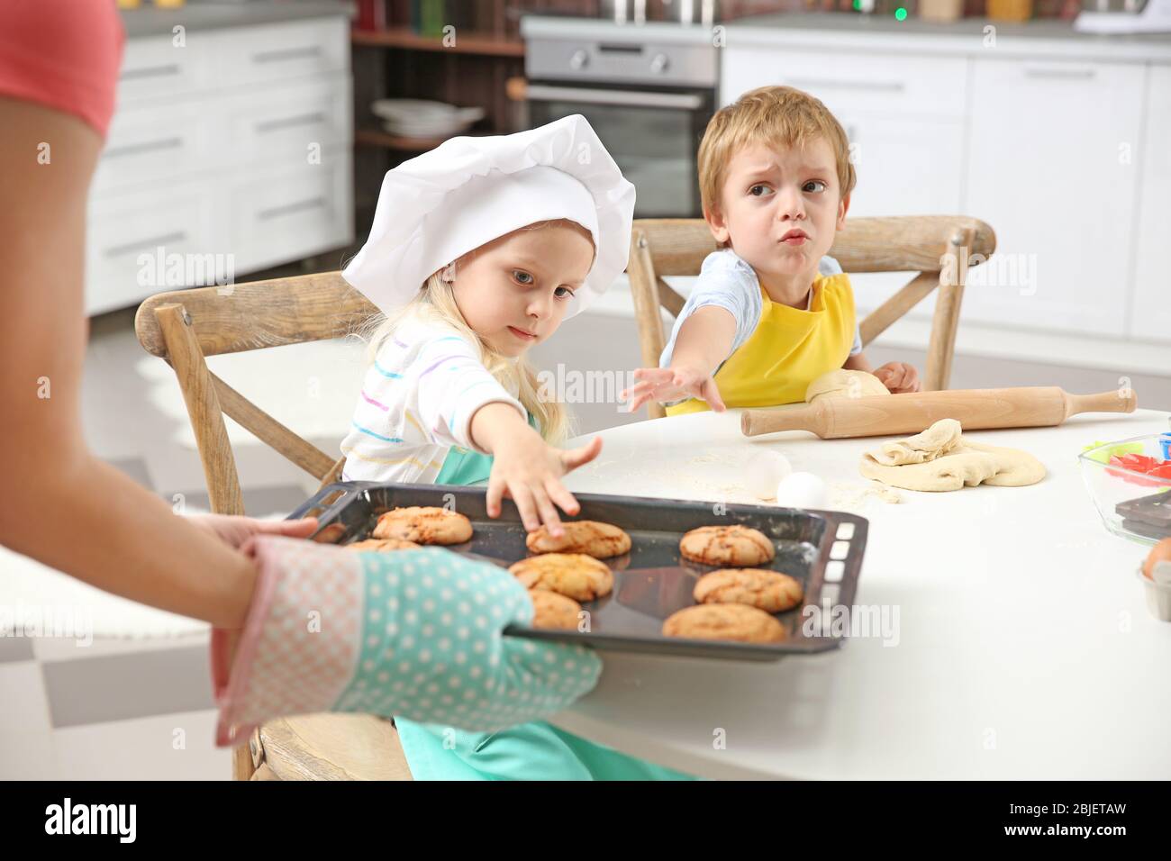 Mother giving to kids fresh baked biscuits Stock Photo - Alamy