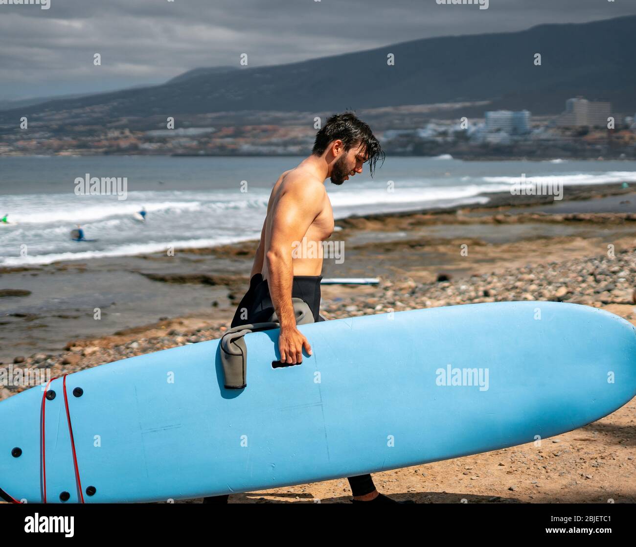 Young and muscular male surfer at the beach posing out of the water ...