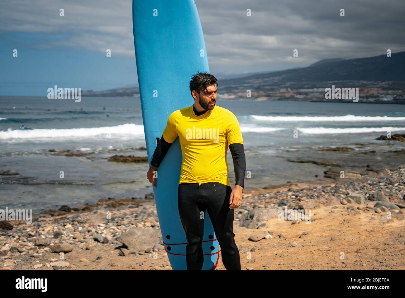 Young and muscular male surfer at the beach posing out of the water ...